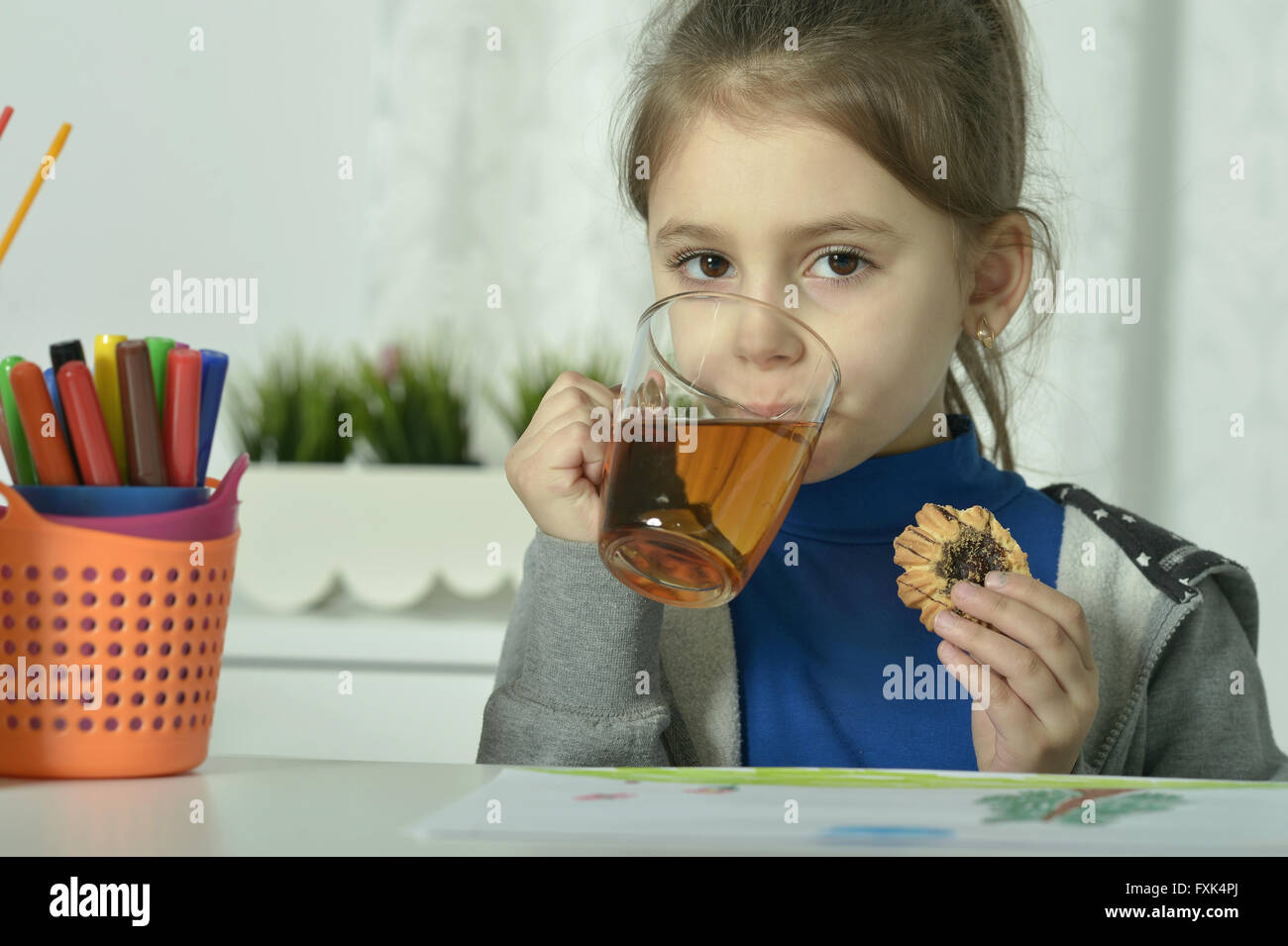girl drinking tea and eating cookie Stock Photo - Alamy