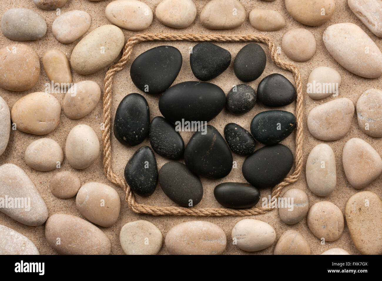 Frame made of rope lying on the sand among the black and white stones ...