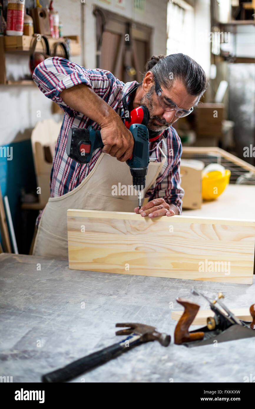 Carpenter drilling a hole in a wooden plank Stock Photo - Alamy