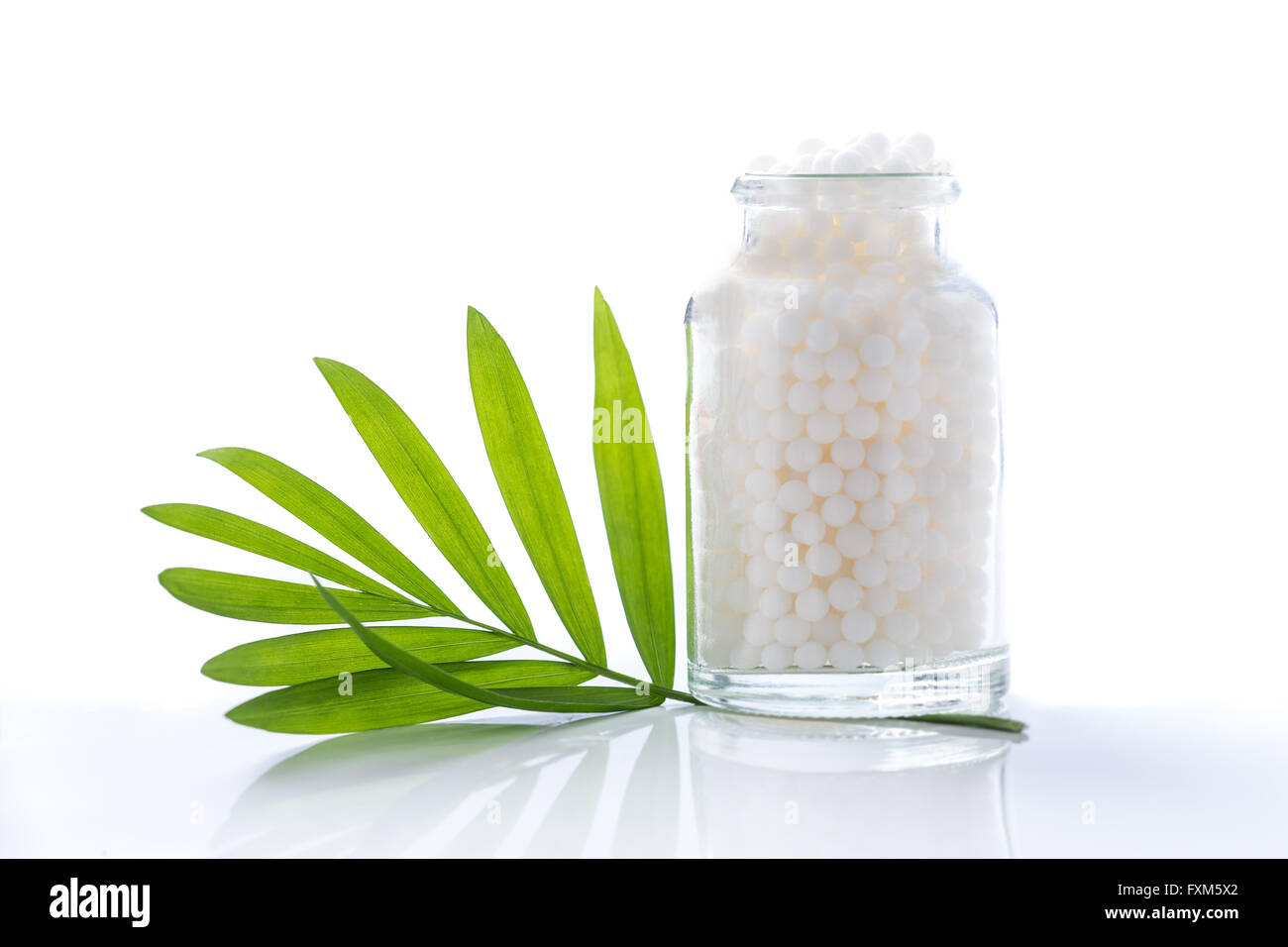 Glass of homeopathy globules and green leaf Stock Photo - Alamy