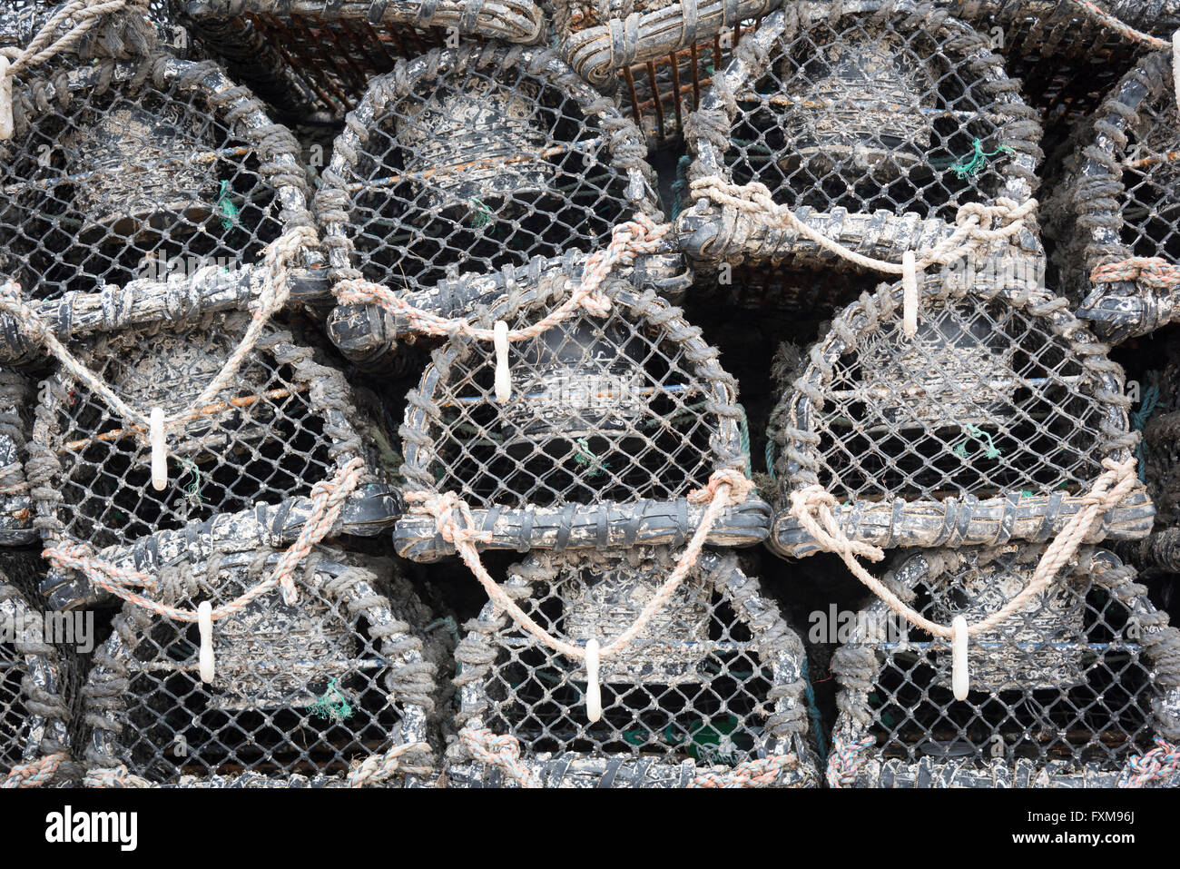 Crab pots and lobster pots or fishing creels stacked on a harbour quay ...