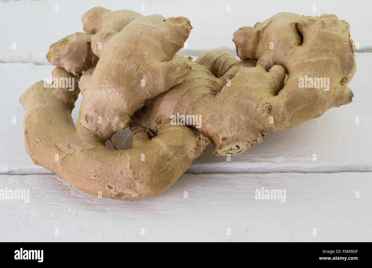 Whole ginger root isolated on white wood table Stock Photo - Alamy