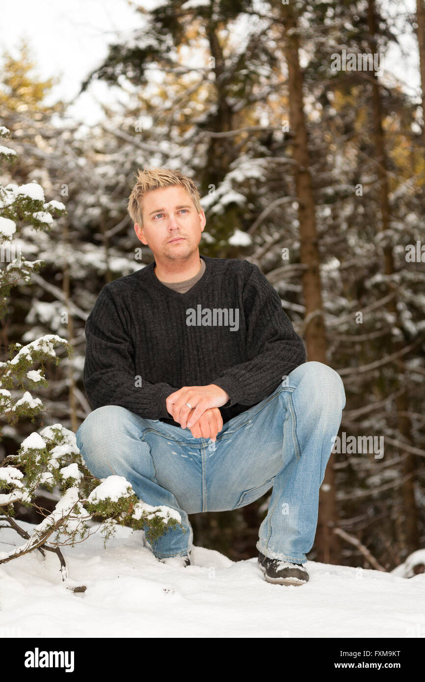 Handsome cool young man outdoors in the snow in the winter wearing warm ...