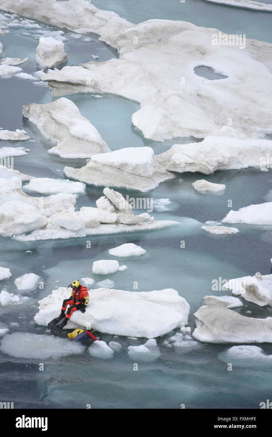 A US Coast Guard rescue diver sits on a piece of sea ice in the Arctic ...