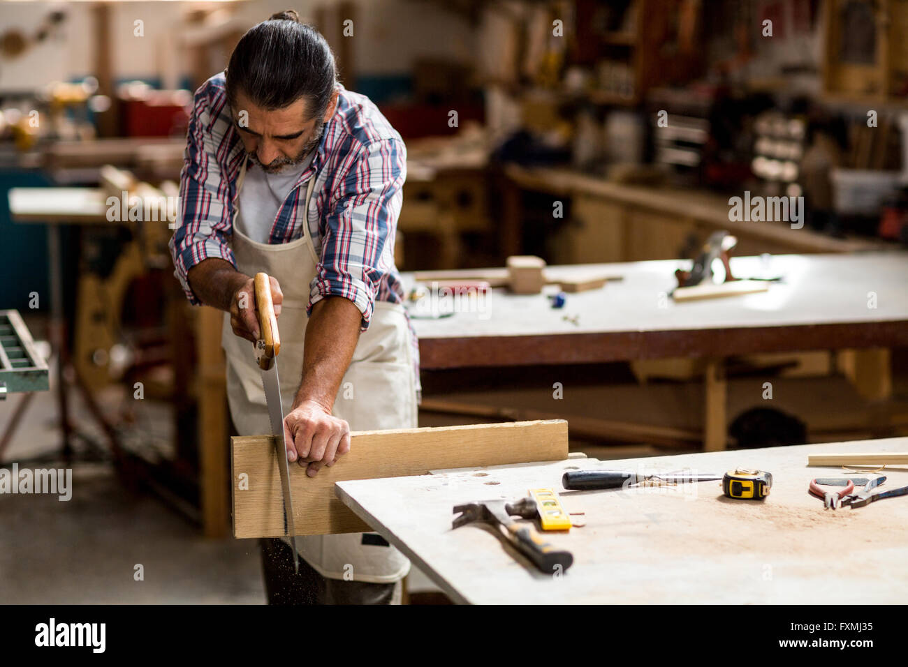 Carpenter cutting plank with hand saw Stock Photo - Alamy