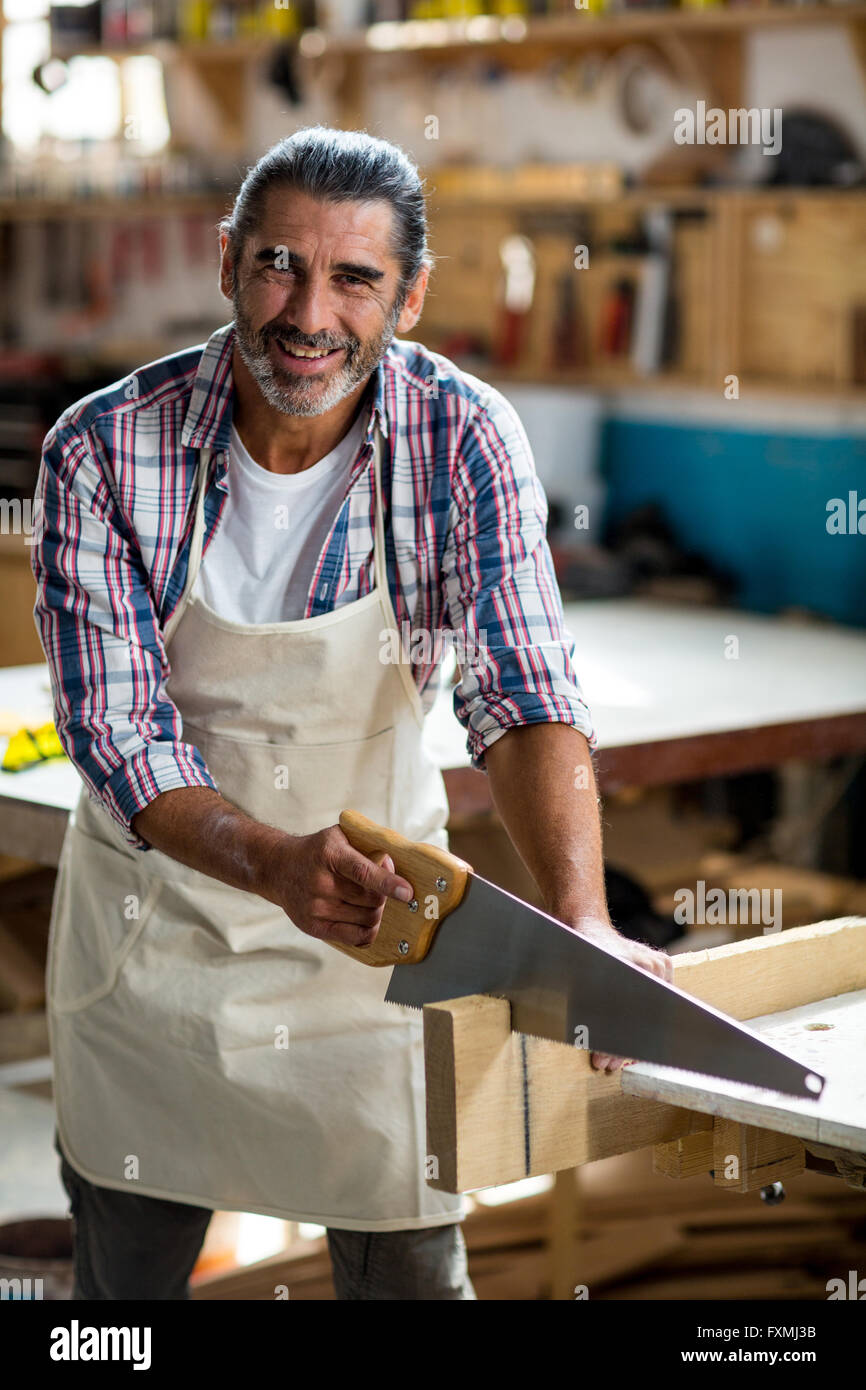 Carpenter cutting plank with hand saw Stock Photo - Alamy