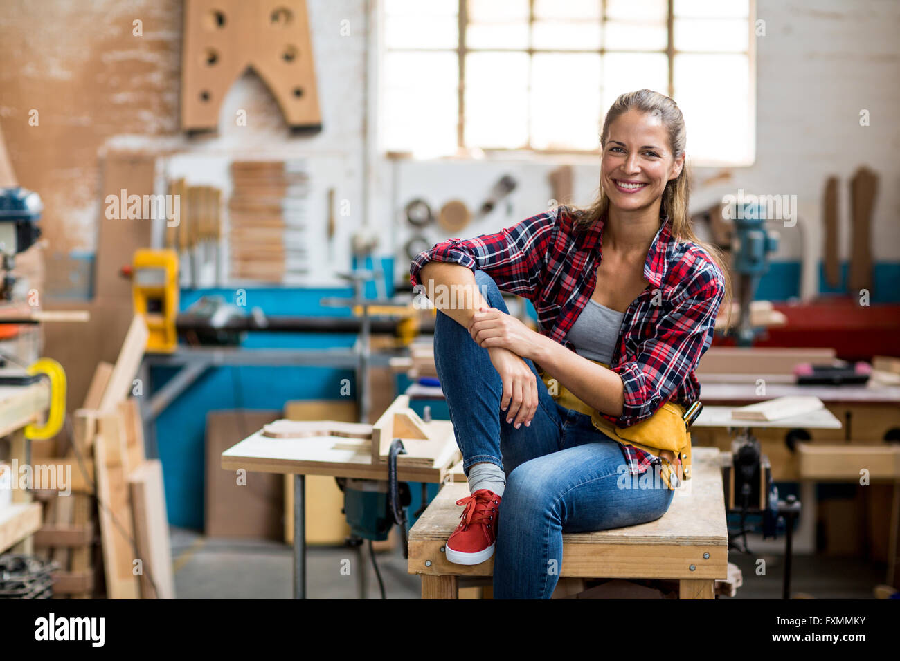 Portrait of female carpenter sitting on table Stock Photo - Alamy