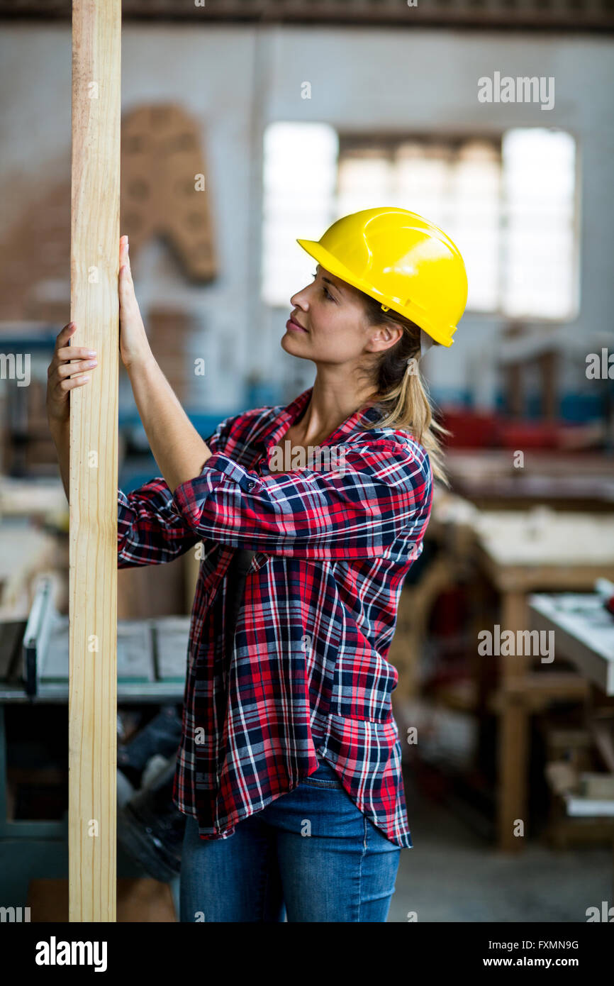 Female carpenter looking at wooden plank Stock Photo - Alamy