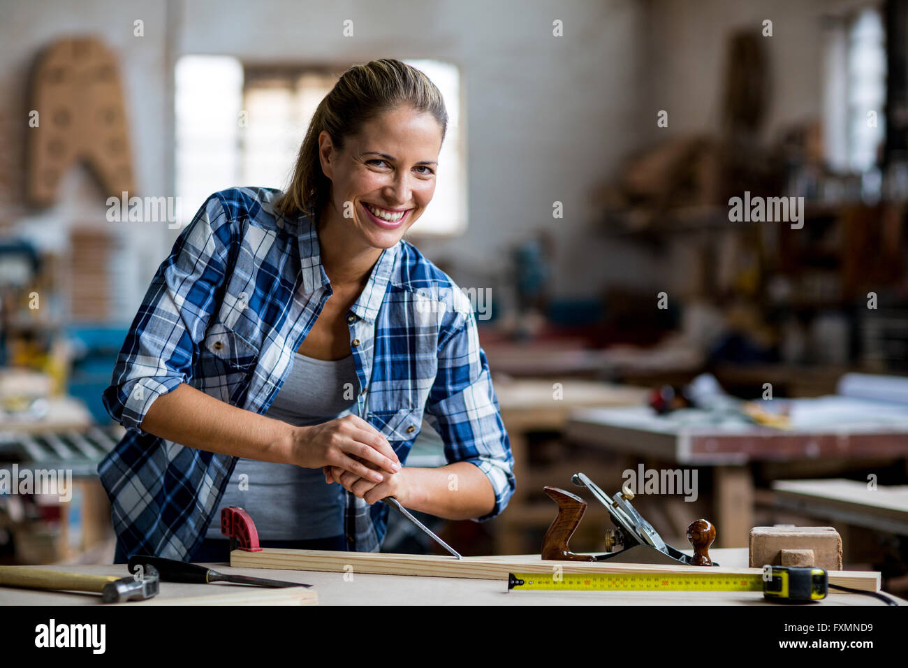 Female carpenter using chisel on wooden plank Stock Photo - Alamy