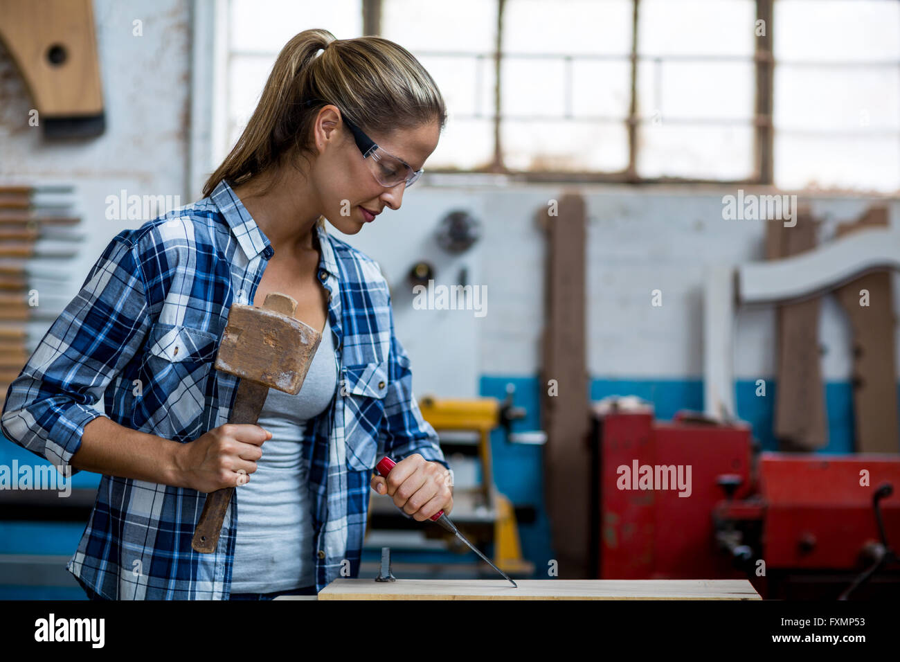 Female carpenter using mallet and chisel Stock Photo - Alamy