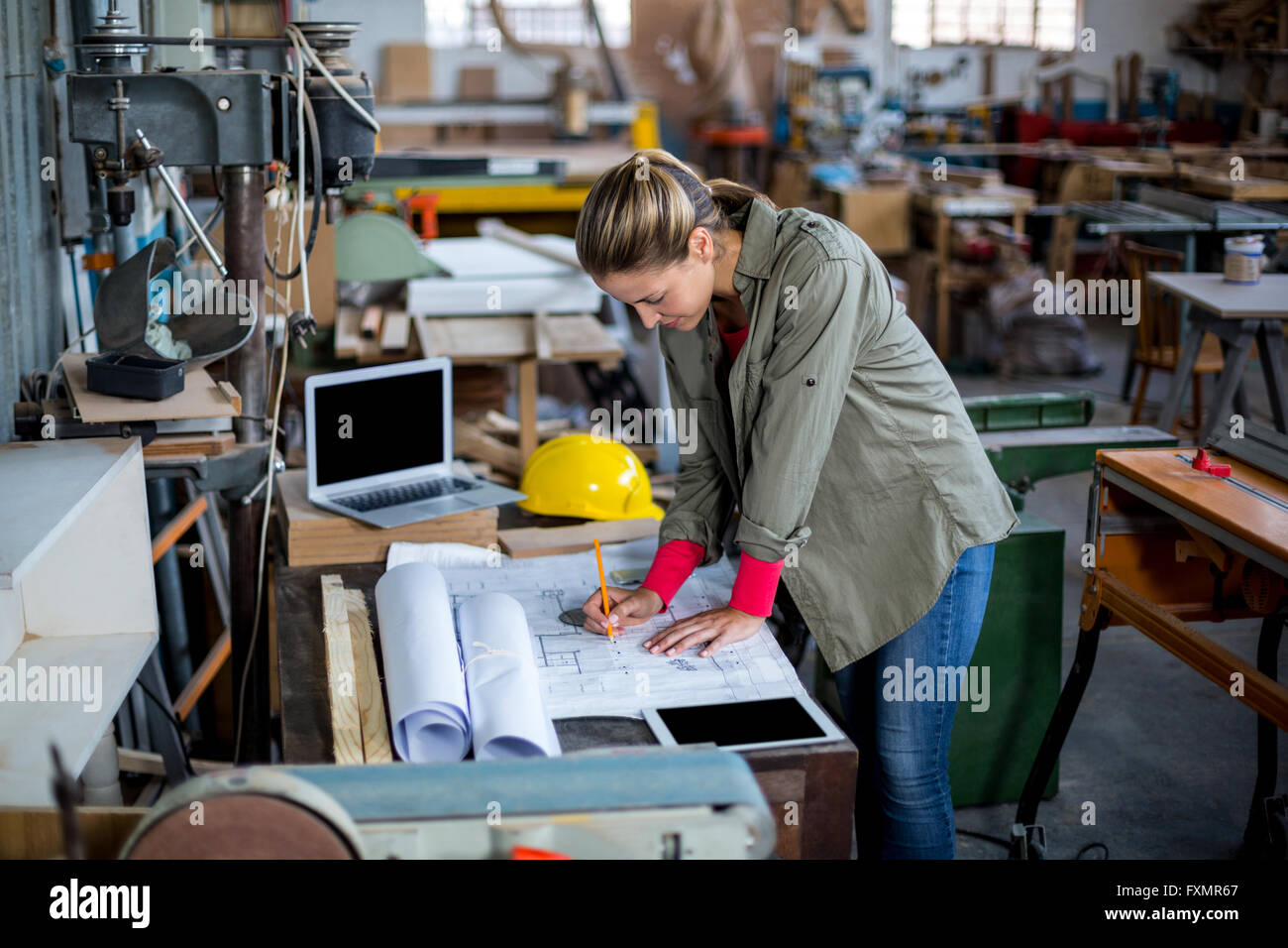Female carpenter marking on blueprint Stock Photo - Alamy