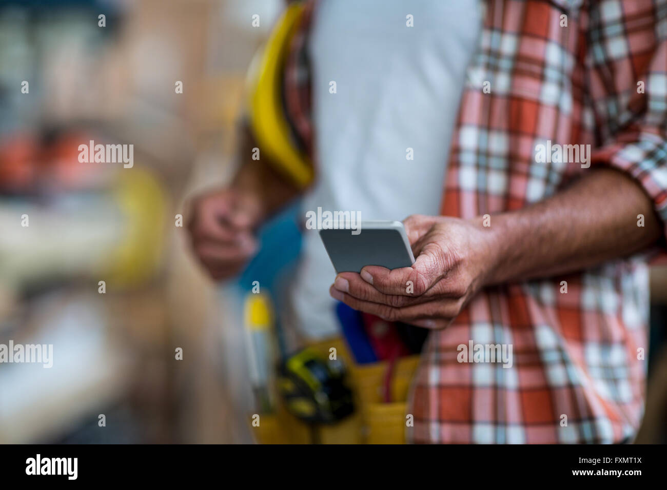 Mid section of carpenter text messaging on mobile phone Stock Photo - Alamy