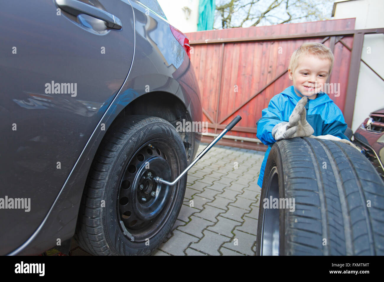 little boy in the exchange of winter tires for summer Stock Photo - Alamy