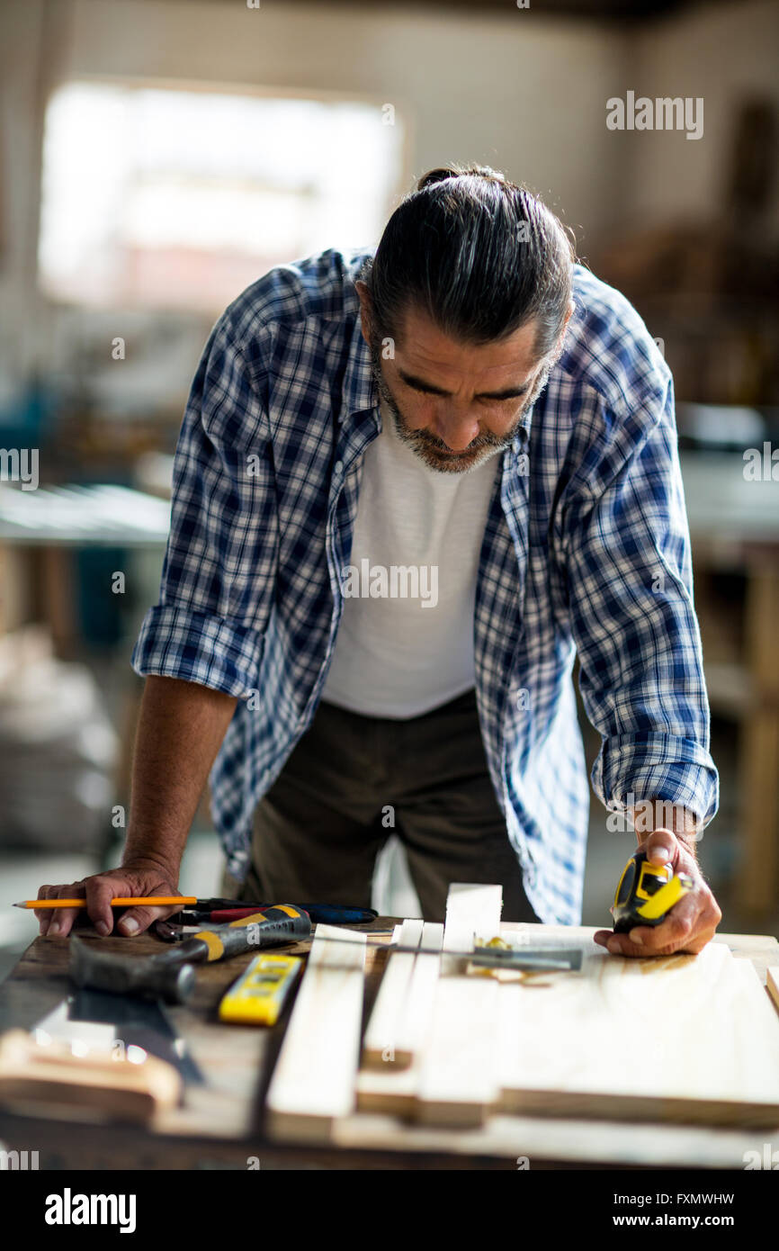Carpenter measuring length of wooden plank Stock Photo - Alamy