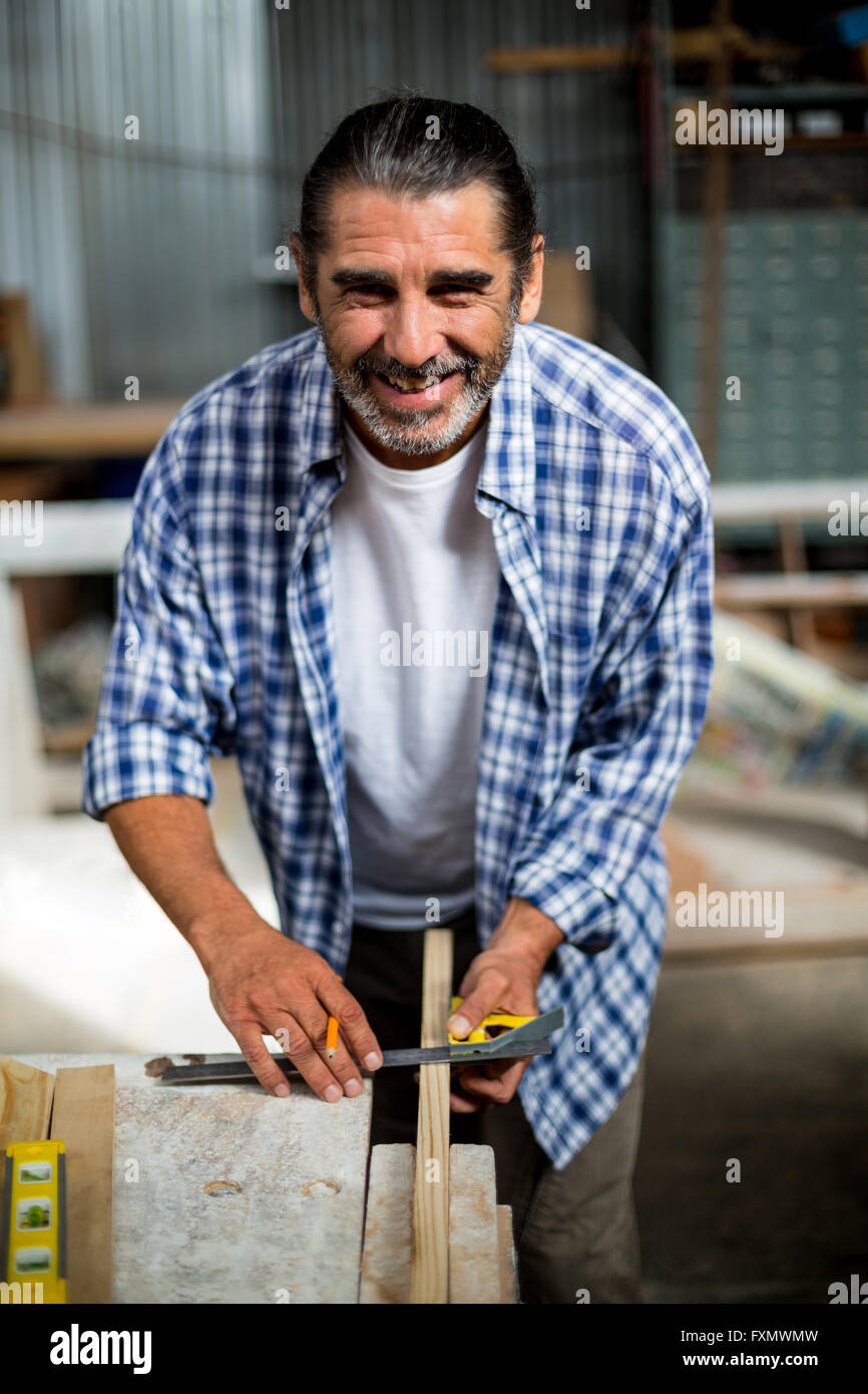 Carpenter measuring a length of wooden plank Stock Photo - Alamy