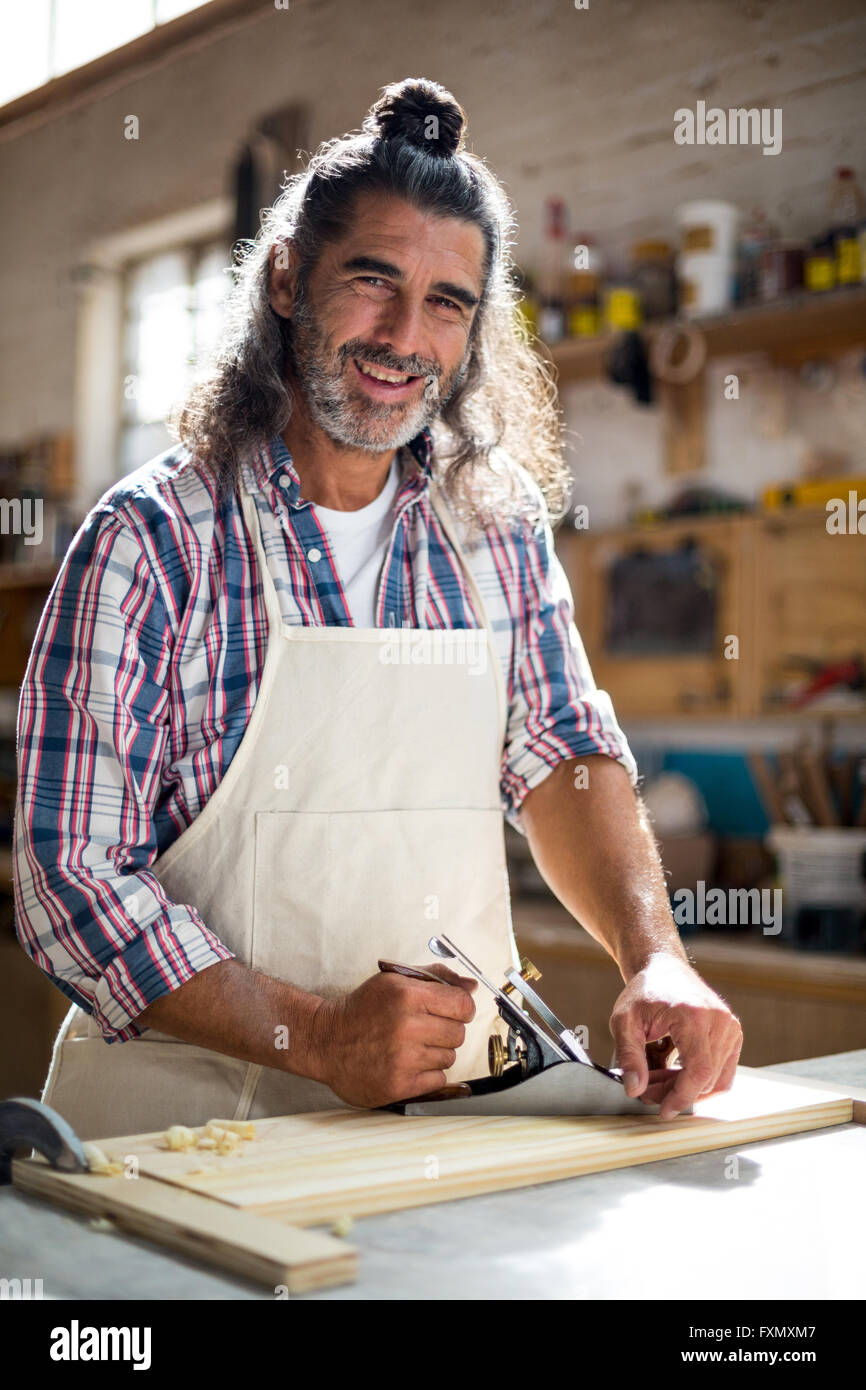 Happy carpenter leveling a timber with jack plane Stock Photo - Alamy