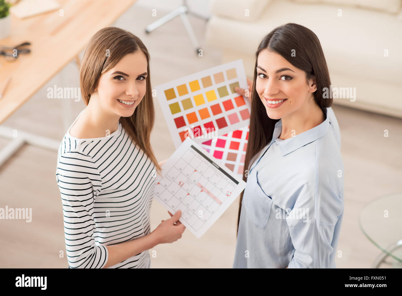 Pleasant working day. Cheerful delighted charming girls holding papers ...