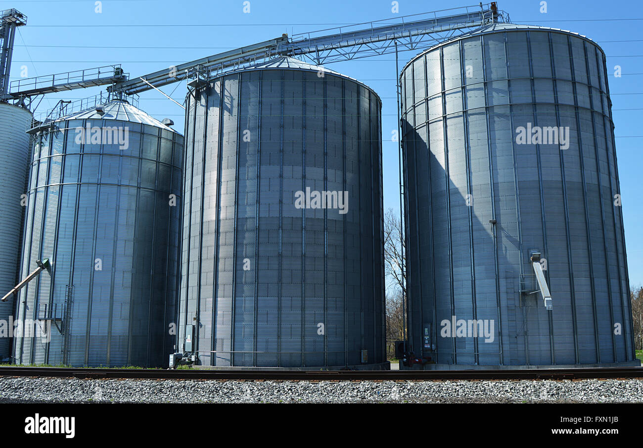 Three metal silos on a clear day in front of railroad tracks Stock ...