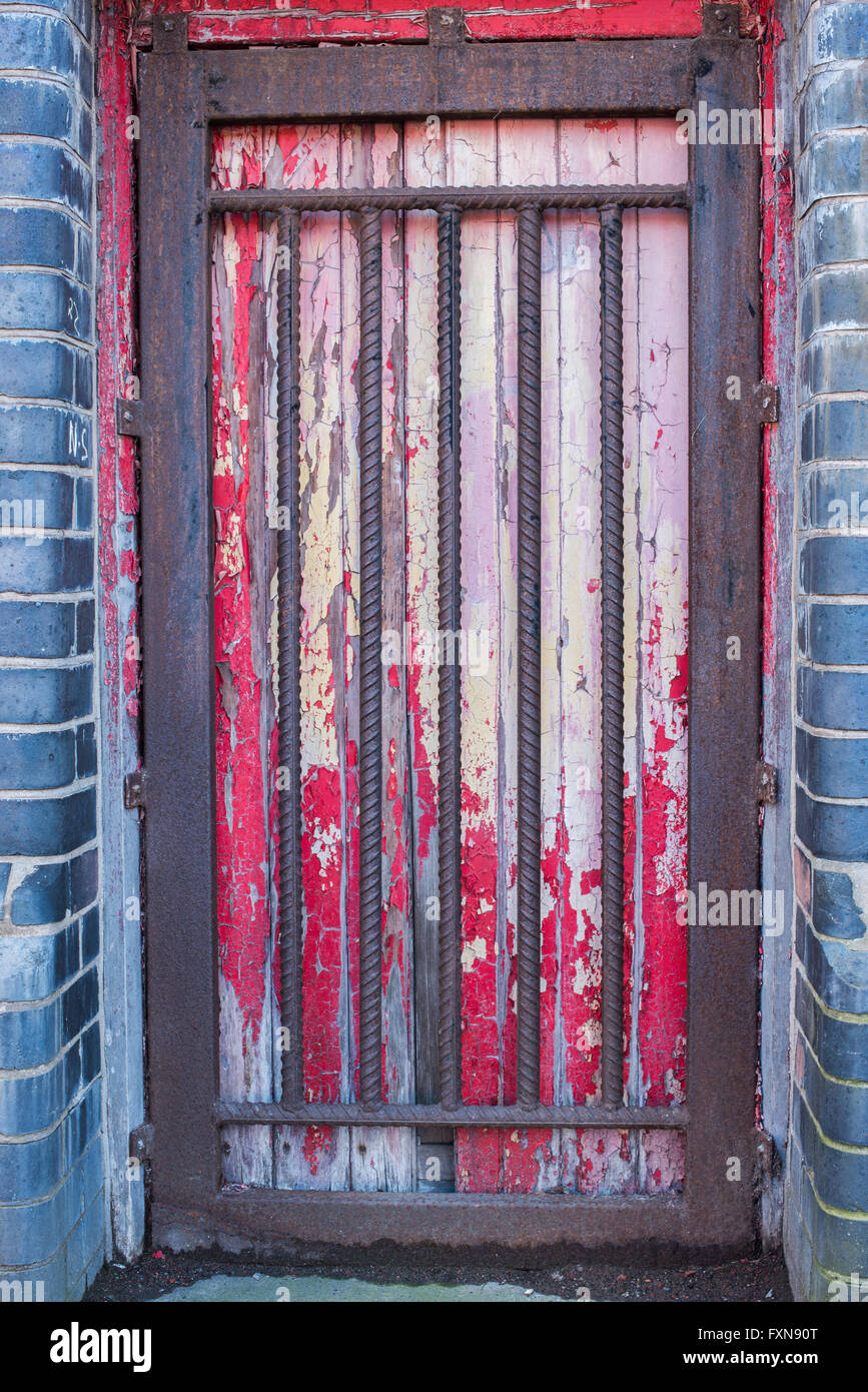 Rusty iron grill over red door with peeling paint Stock Photo - Alamy