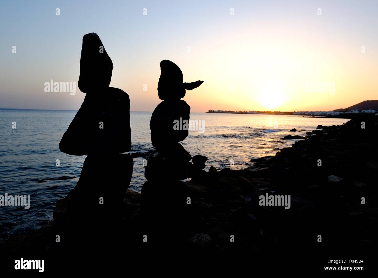 balance rocks and pebbles on a beach at dusk silhouetted against the ...