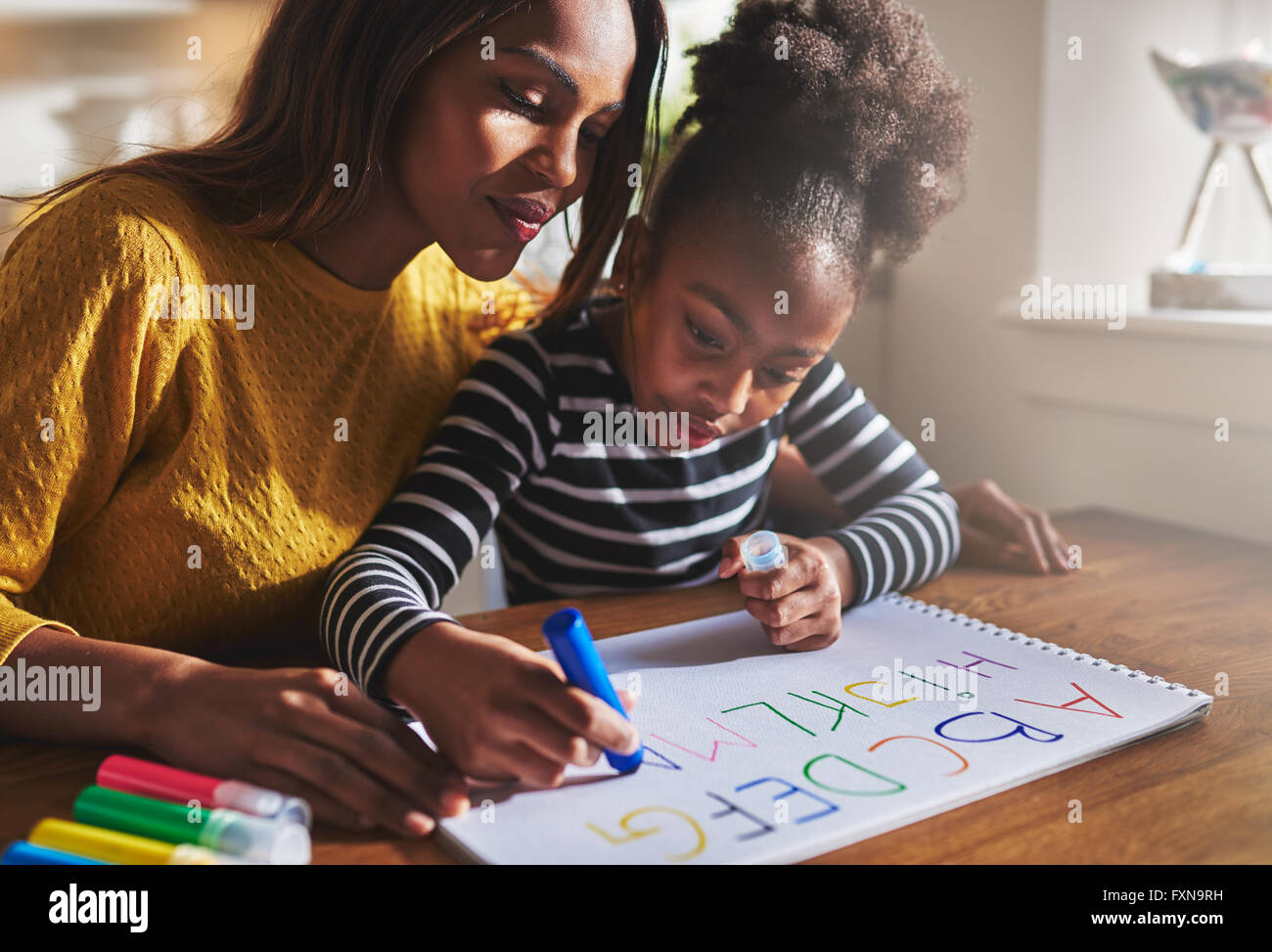 Little girl writing the alphabet with mother at home Stock Photo - Alamy