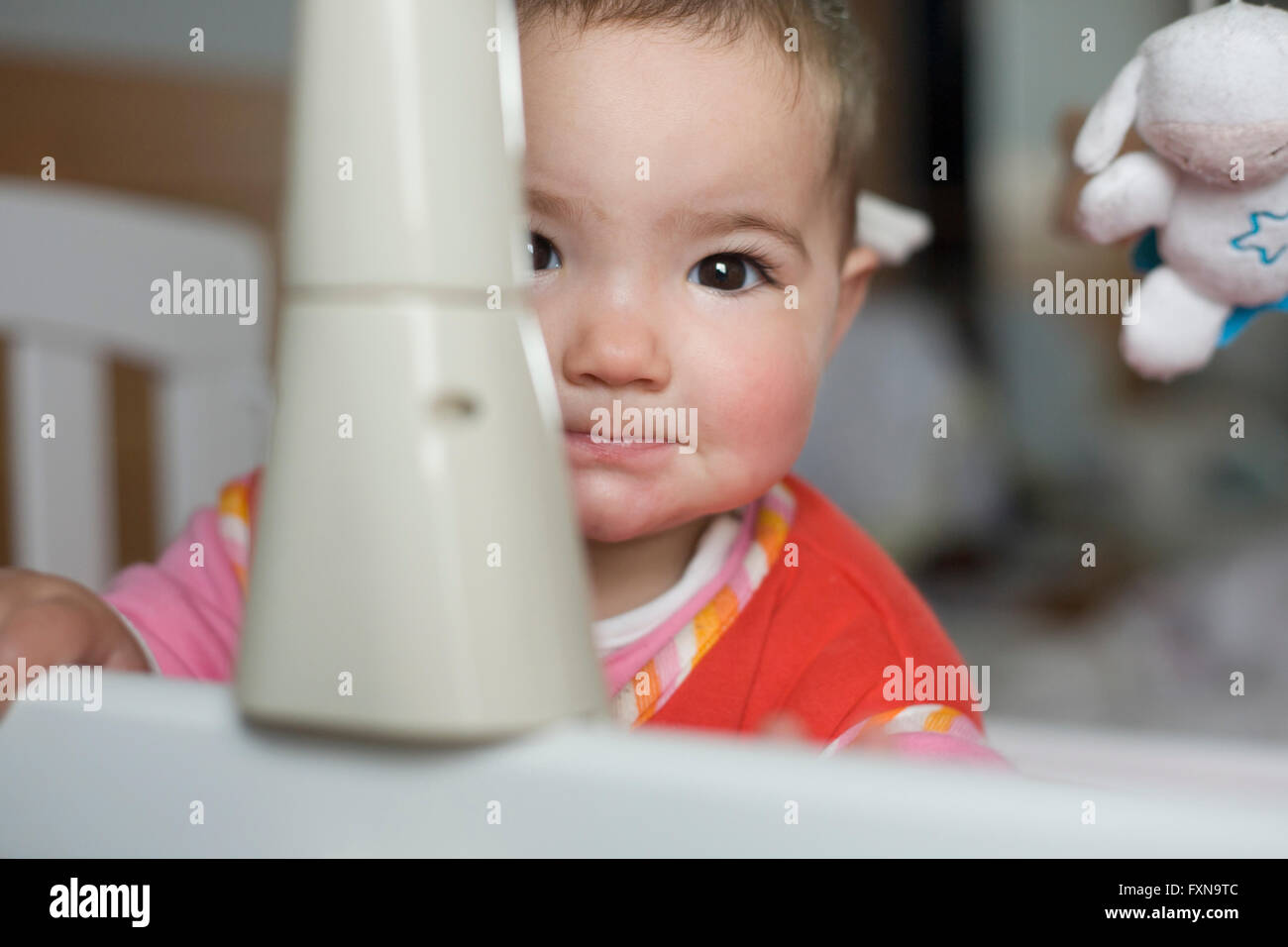 Ten month baby girl playing hide-and-go-seek behind mobile toy Stock ...