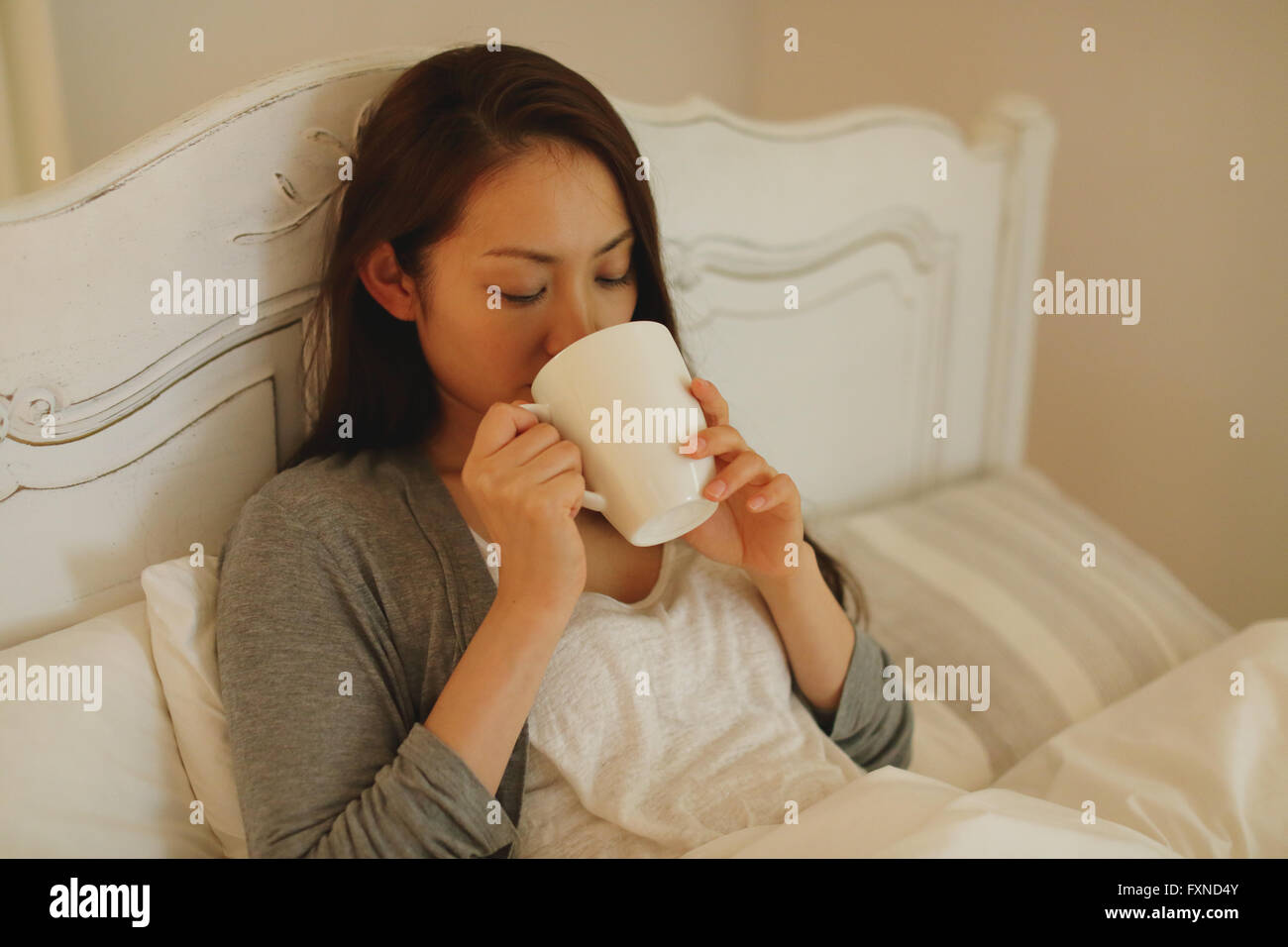 Young attractive Japanese woman drinking coffee in bed Stock Photo - Alamy