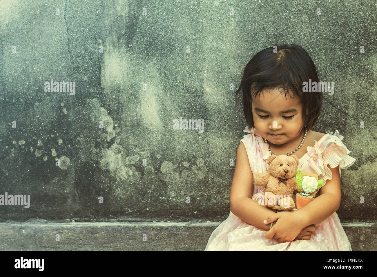 Girls sit hugging teddy side wall of the old Stock Photo - Alamy