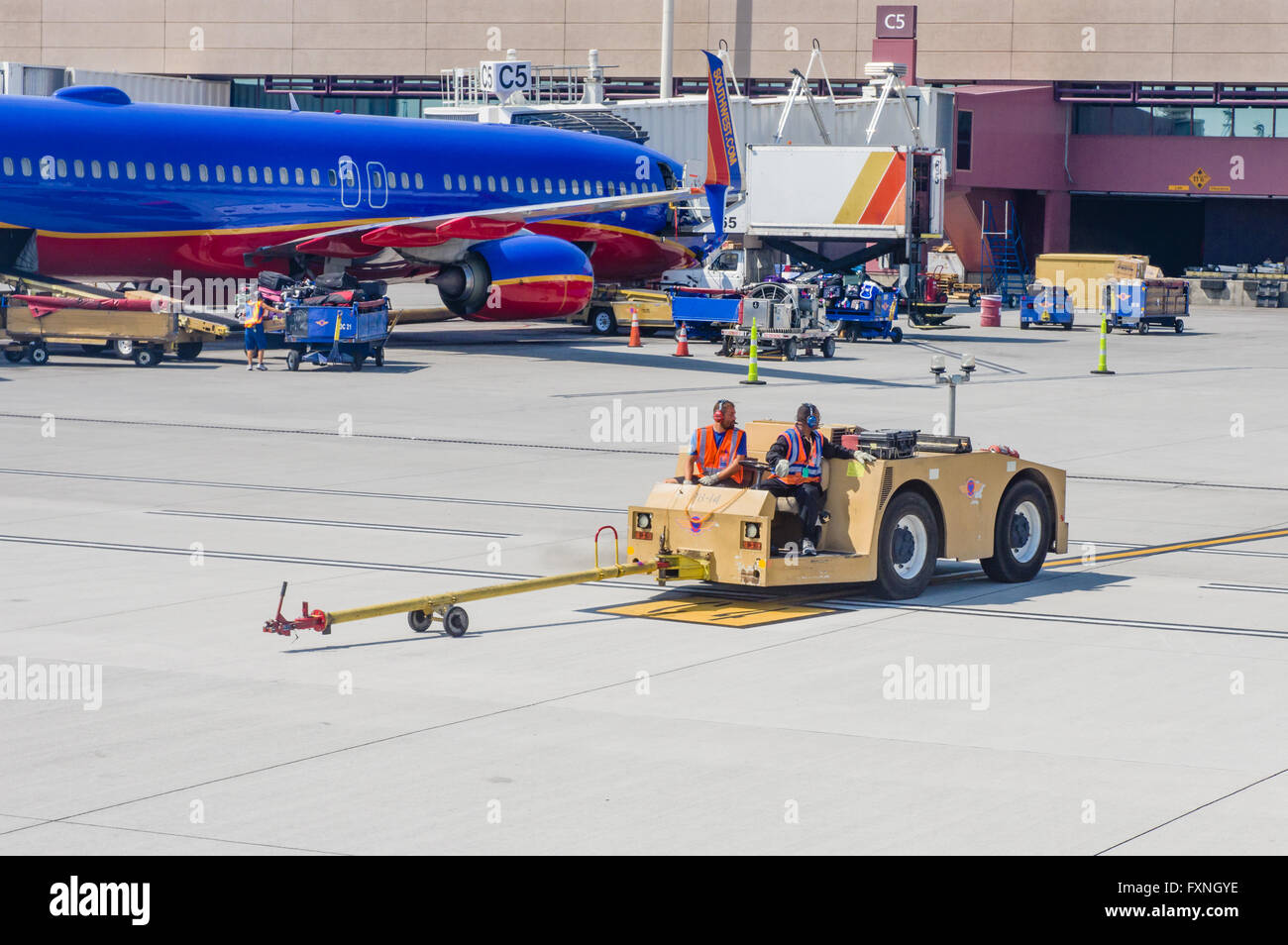 Workers reposition an aircraft tug after pushing back a jet airpliner ...