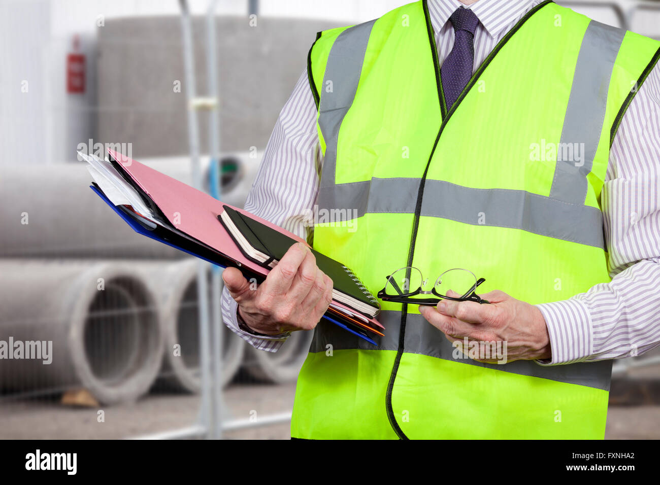 Building surveyor in high visibility vest carrying work folders and ...