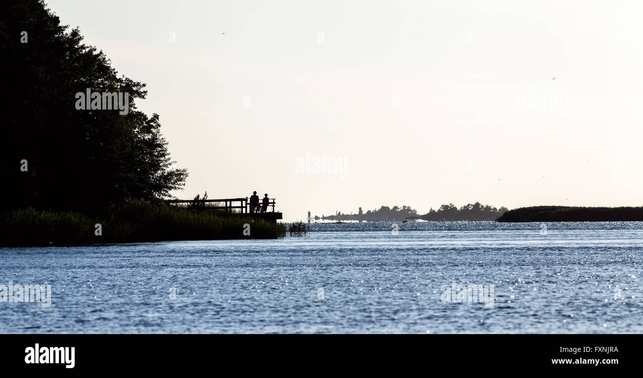 People rest on a bridge far away. Inlet from the sea. Silhouettes by ...