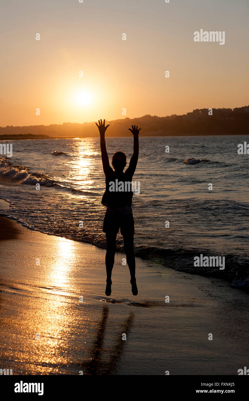 WOMAN JUMPING IN FRONT OF THE SUN ON THE BEACH Stock Photo - Alamy
