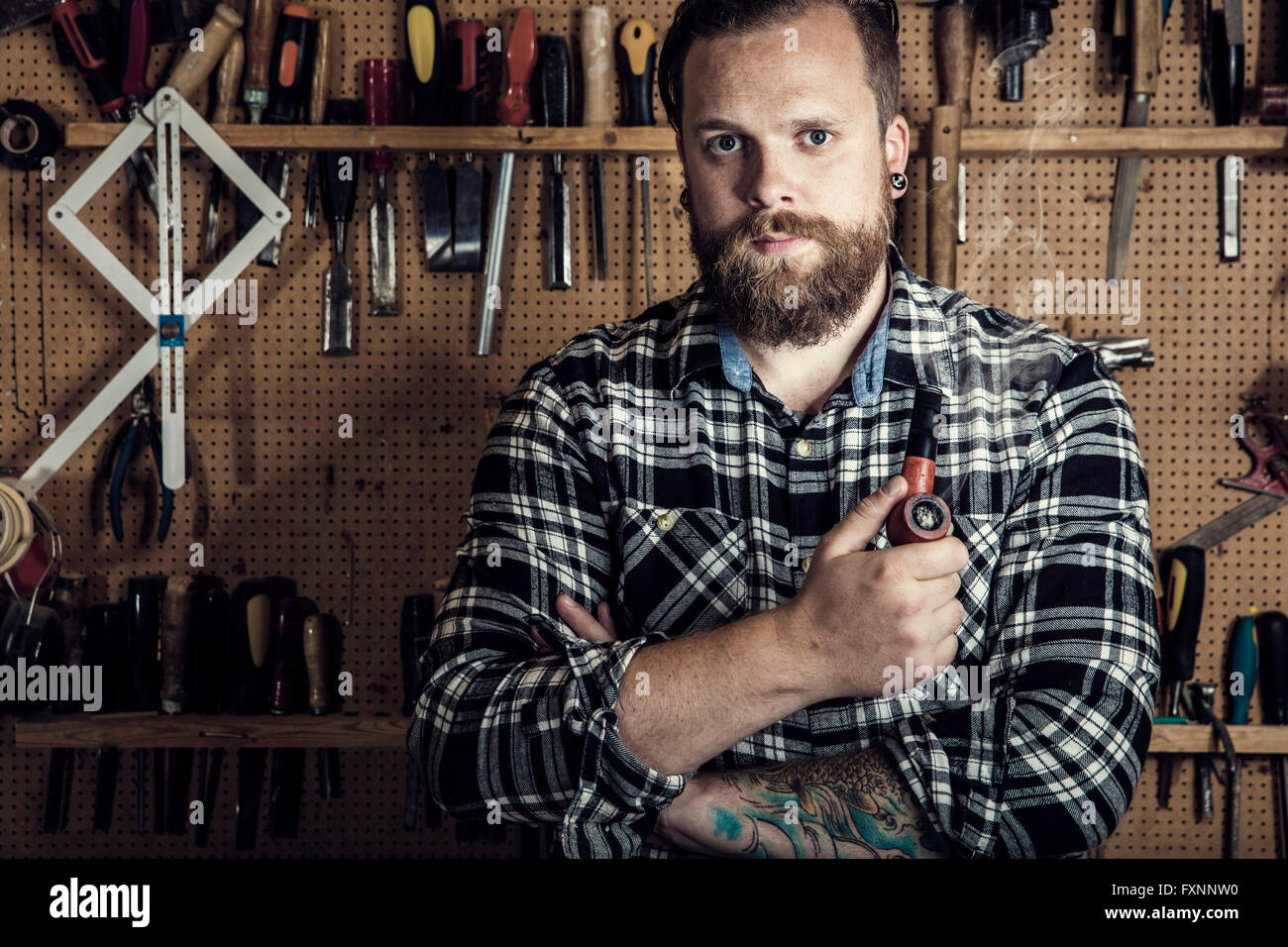 Environmental portrait of a man smoking pipe in wood workshop Stock ...