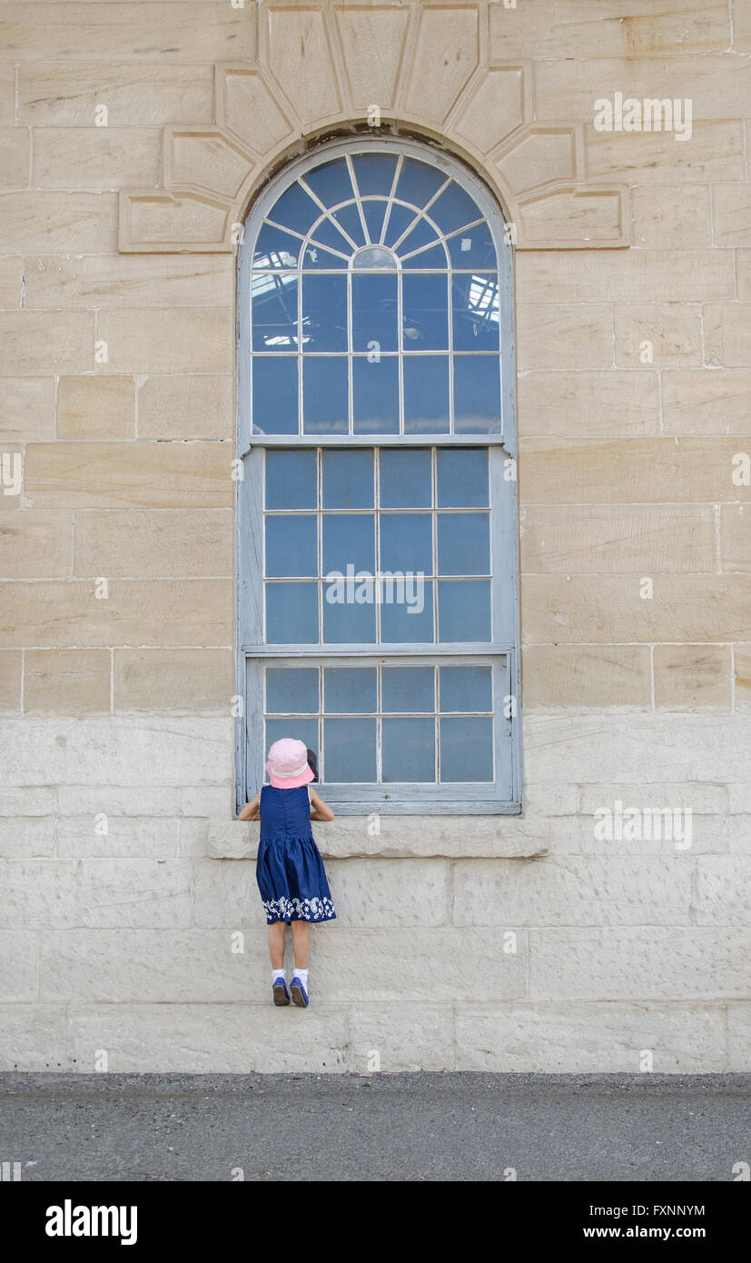 Curious child looking through a window Stock Photo - Alamy
