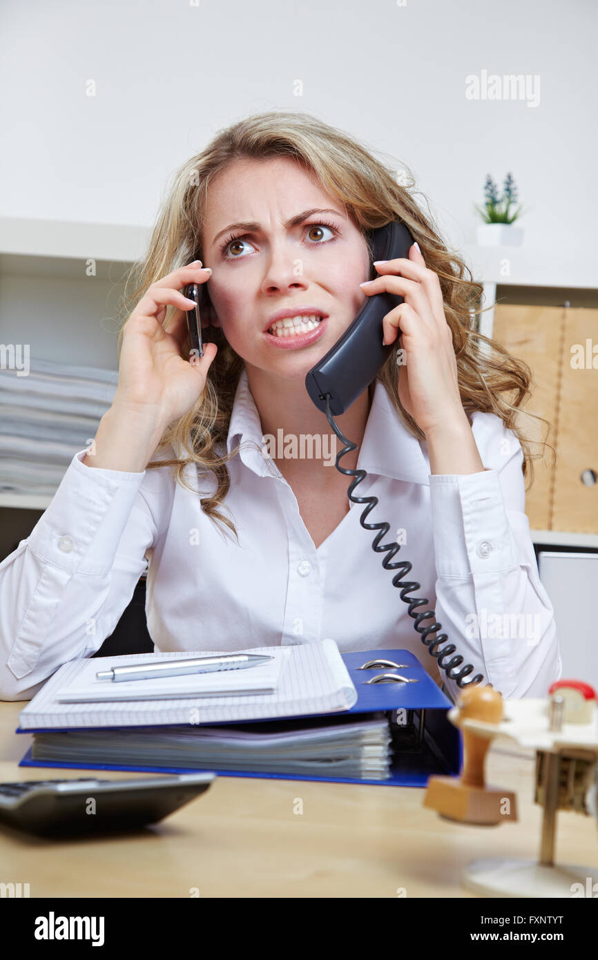 Angry business woman in her office on two phones at the same time Stock ...
