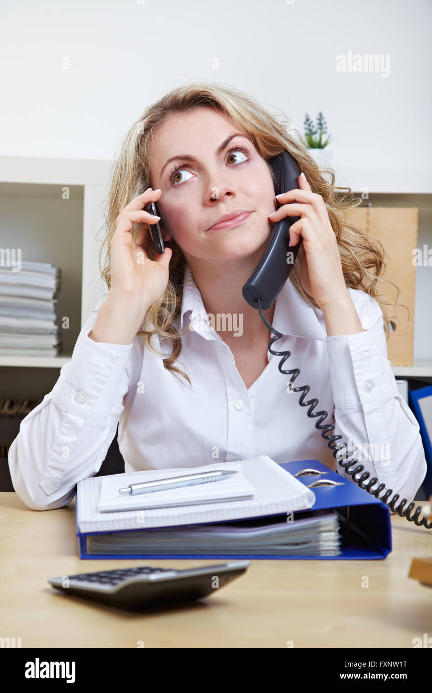 Stressed business woman in the office using two phones simultaneously ... Stressed business woman in the office using two phones simultaneously ...