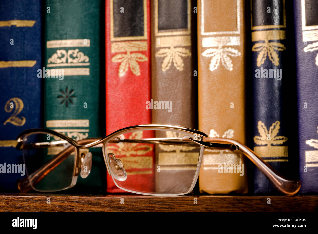 Glasses in a gold frame on a book shelf Stock Photo - Alamy
