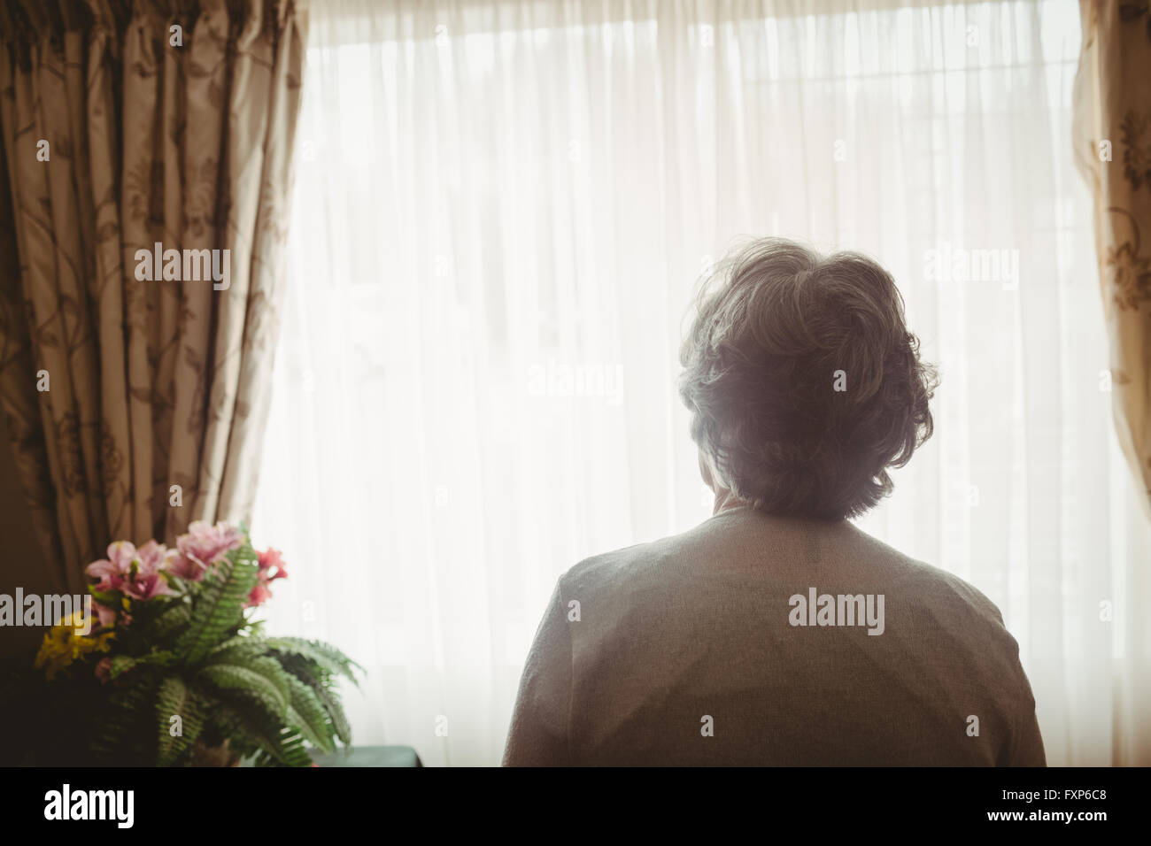 Senior woman looking out of the window Stock Photo - Alamy