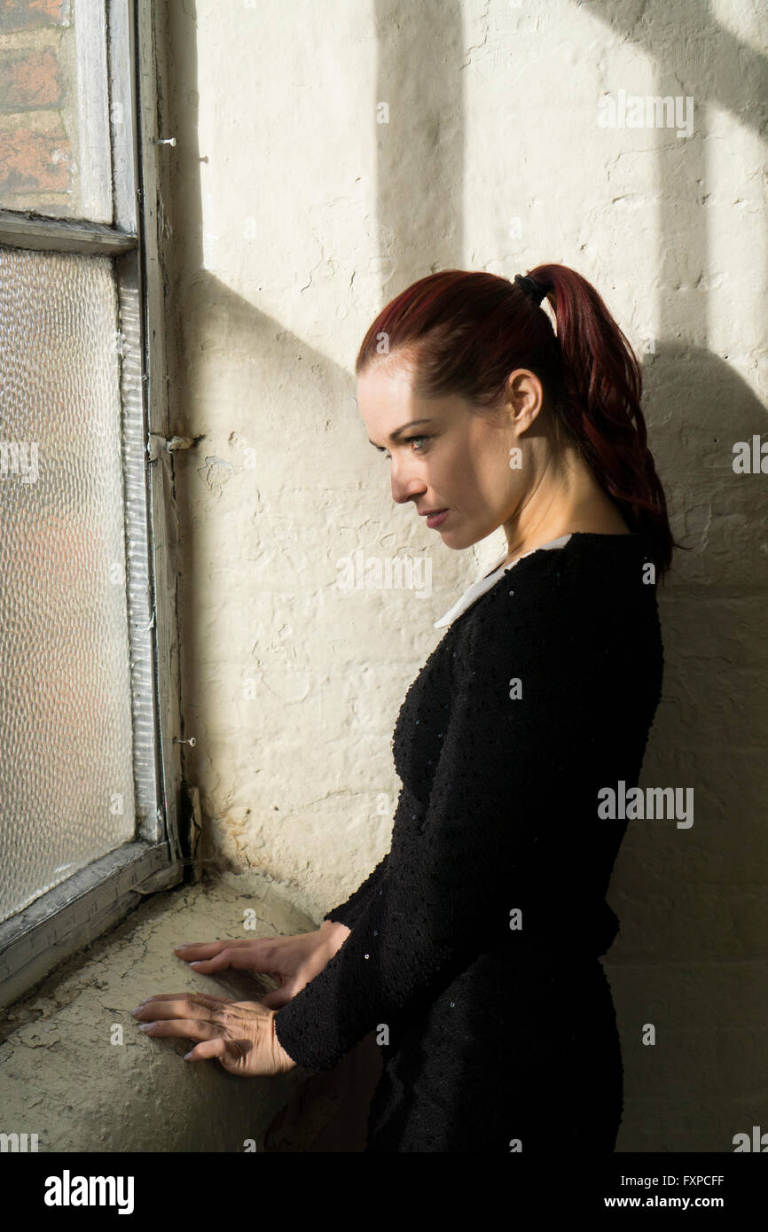Sad woman looking out of the window Stock Photo - Alamy