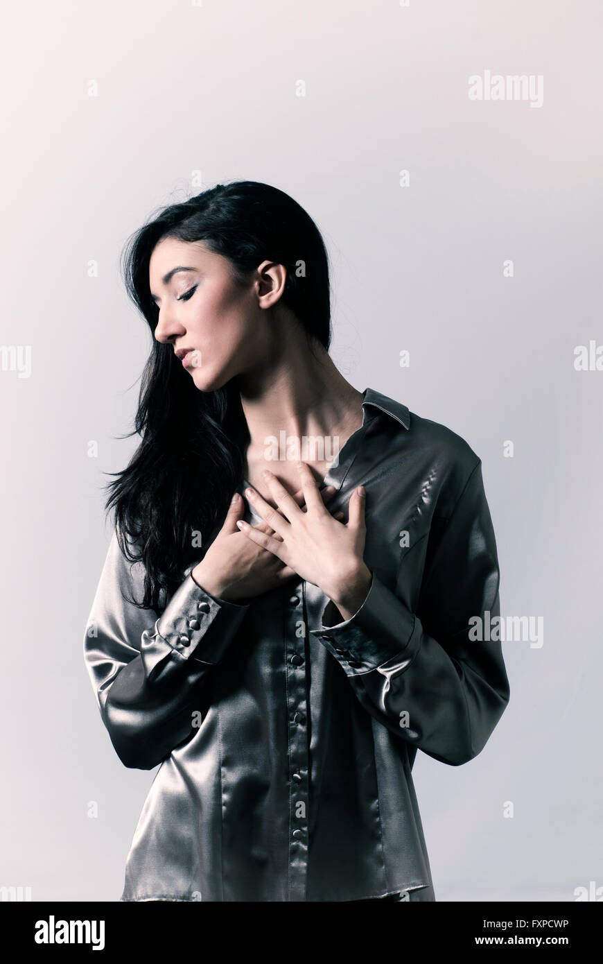 Sad young woman hands over heart looking away Stock Photo - Alamy