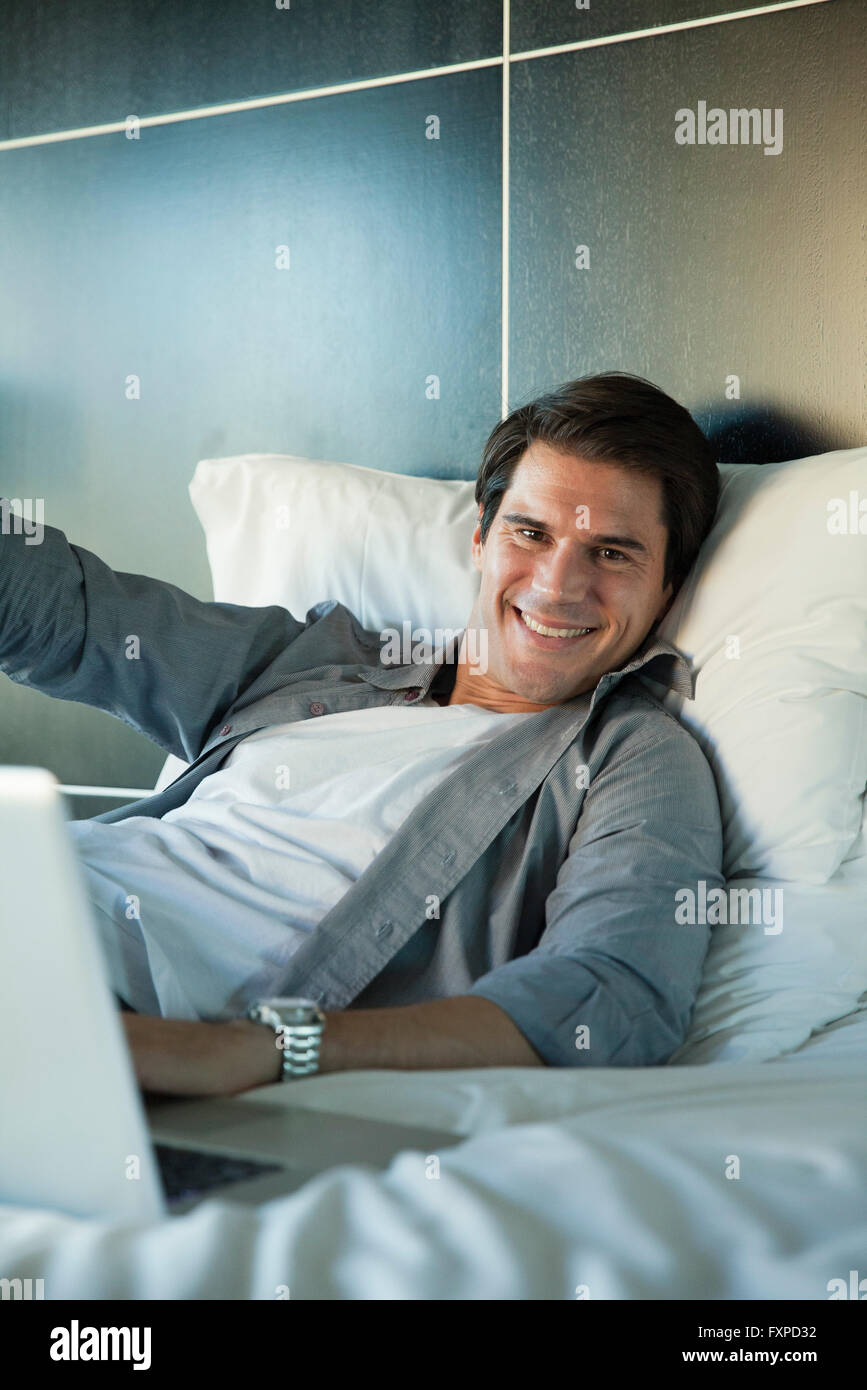 Man lying on bed, smiling cheerfully, portrait Stock Photo - Alamy
