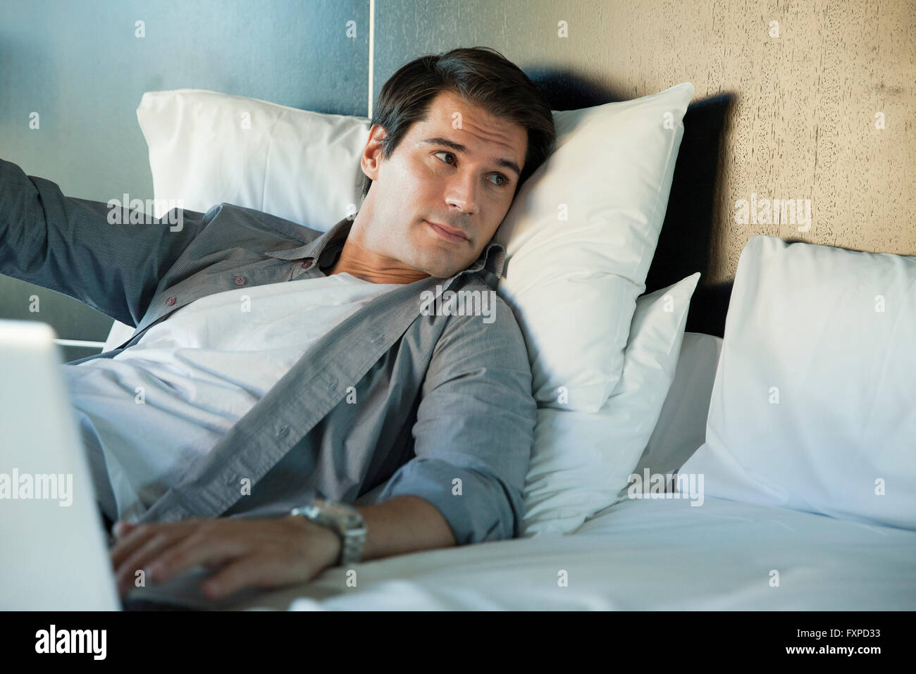 Man relaxing in bed with laptop computer Stock Photo - Alamy