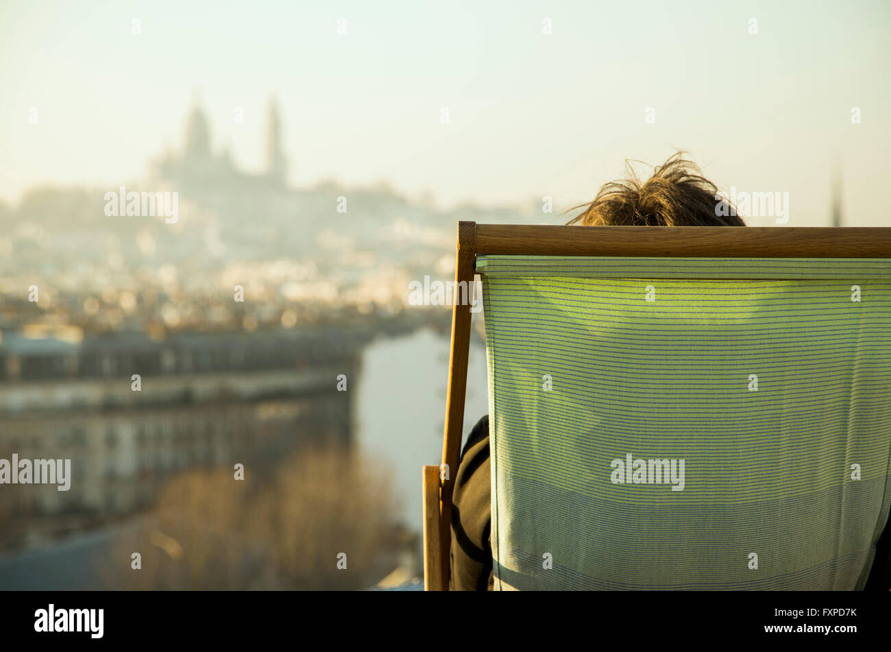 Person sitting in deckchair, looking at view of city Stock Photo - Alamy