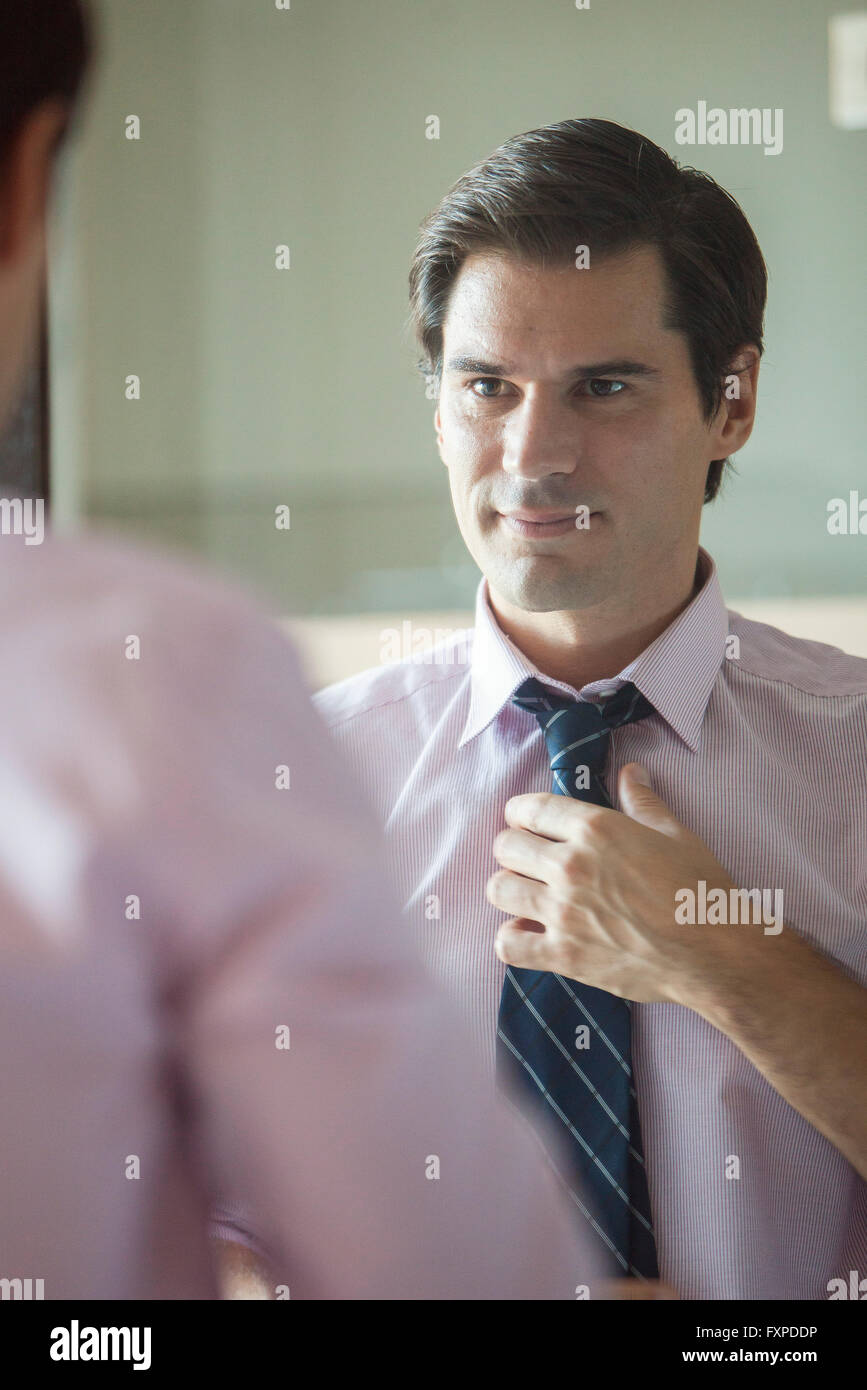 Man adjusting his tie in mirror Stock Photo - Alamy
