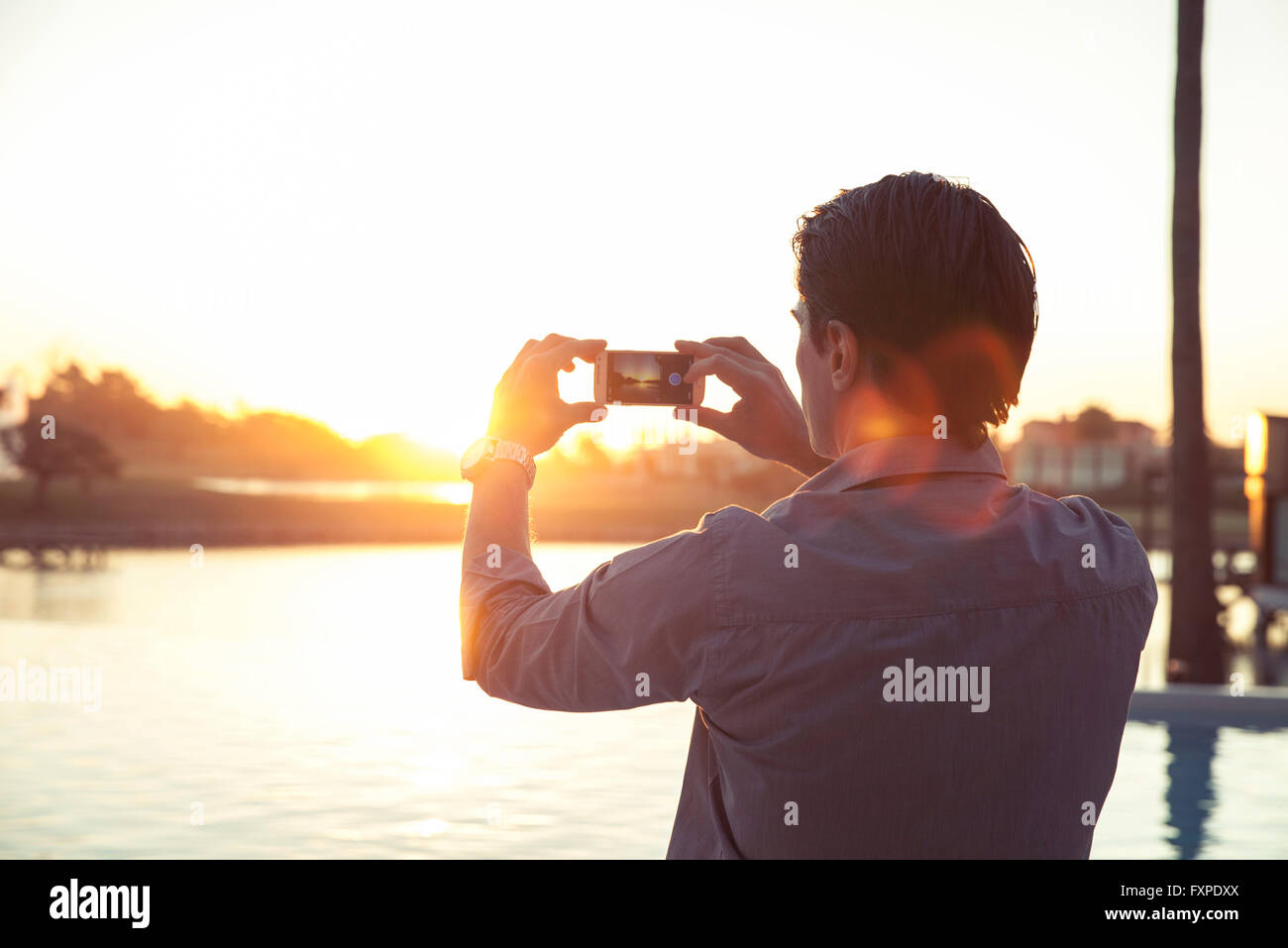 Man photographing sunset with smartphone Stock Photo - Alamy