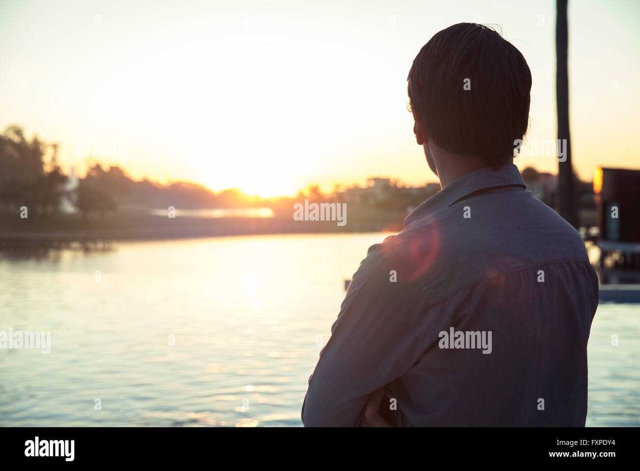 Man looking at sunset, rear view Stock Photo - Alamy