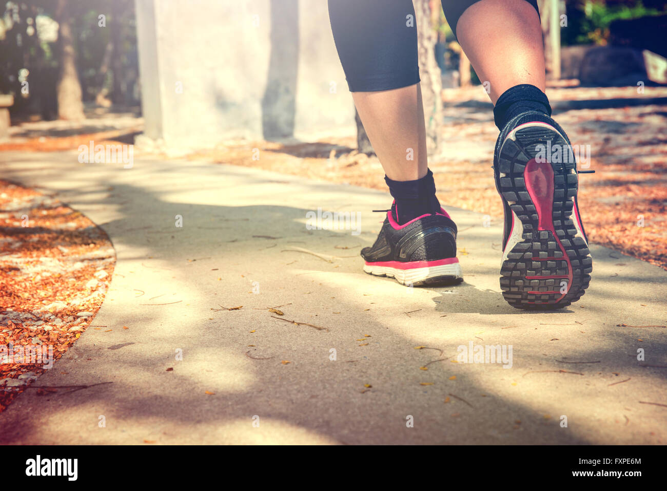 Running feet of young woman going by concrete trail in the park - in ...