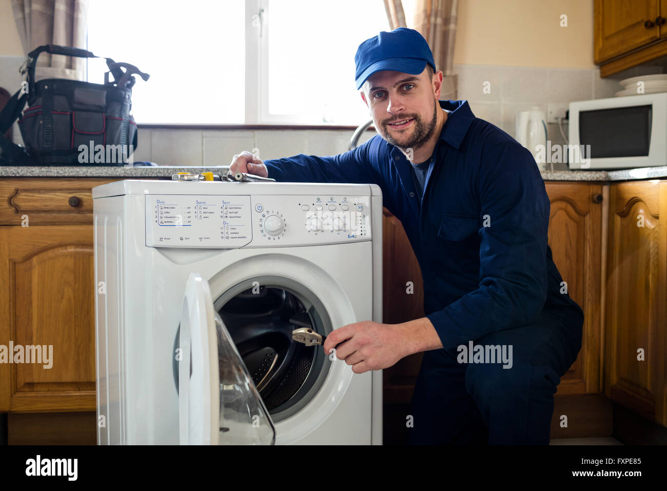 Portrait of handyman repairing a washing machine Stock Photo - Alamy