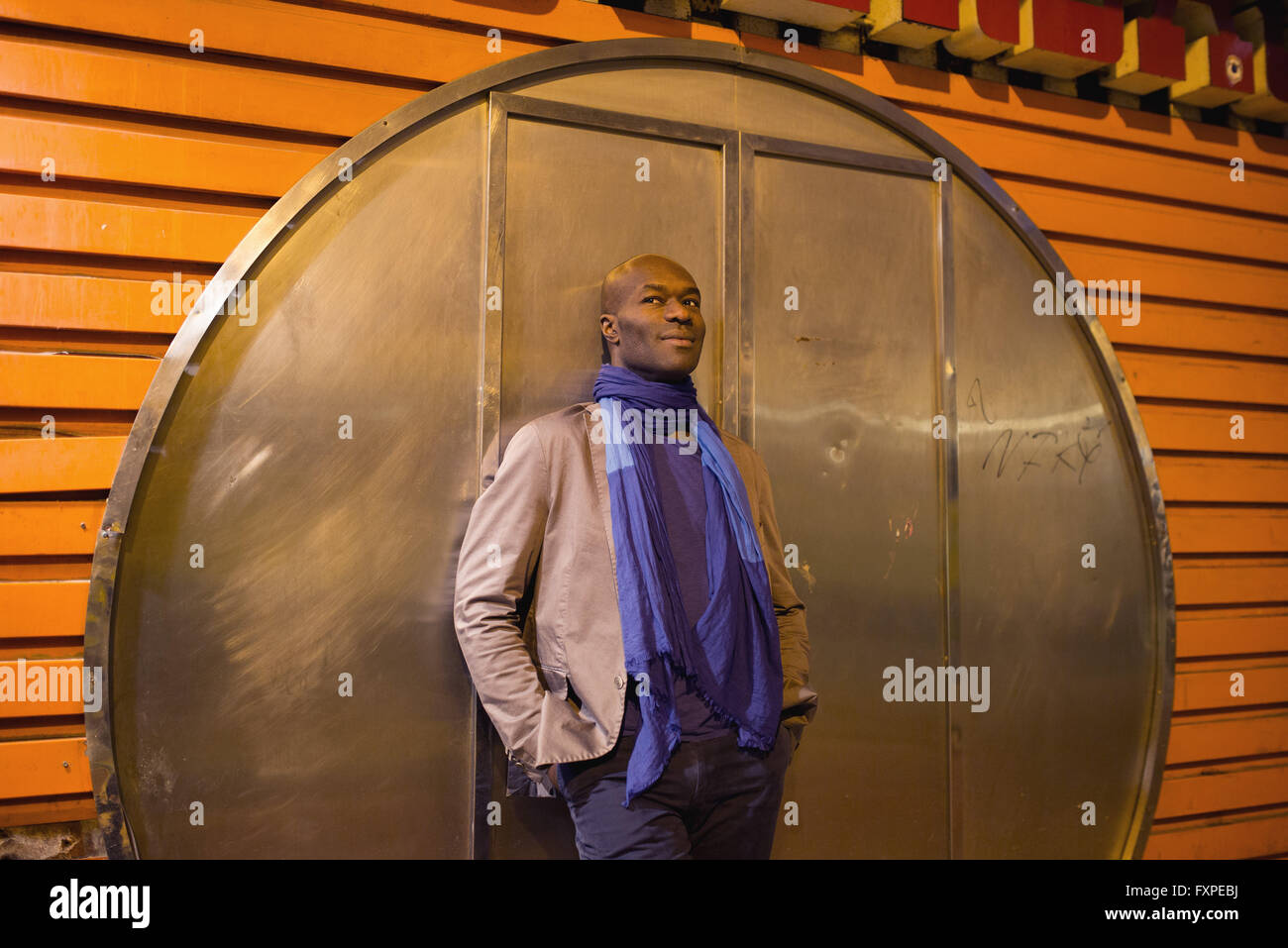 Man leaning against wall with hands in pockets Stock Photo - Alamy
