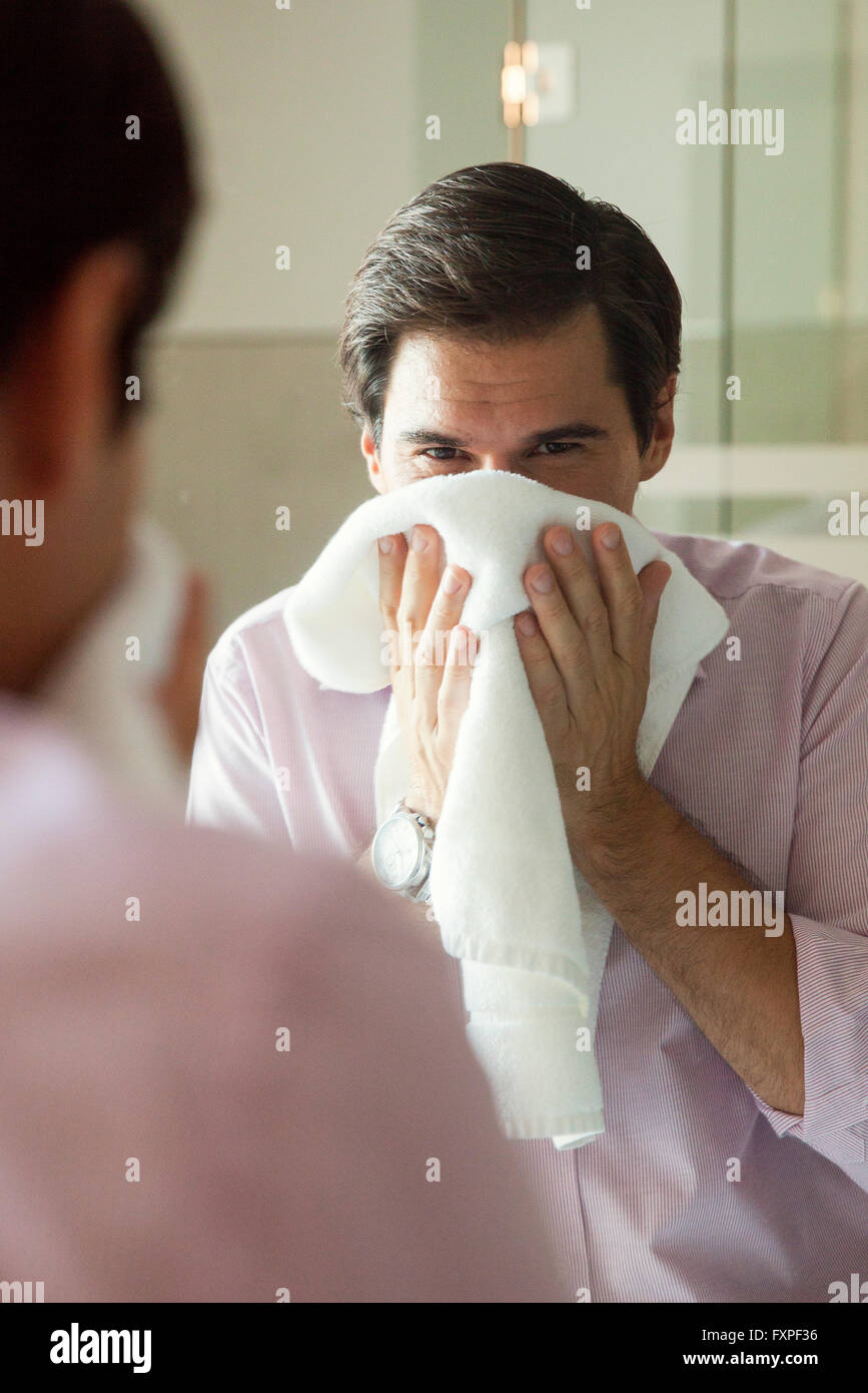 Man looking in mirror, drying his face with a towel Stock Photo - Alamy